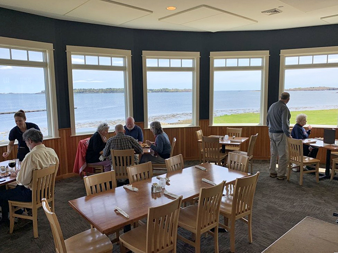 The dining room's nautical blues and warm woods create the perfect backdrop for enjoying Maine's coastal bounty while waves lap gently outside.