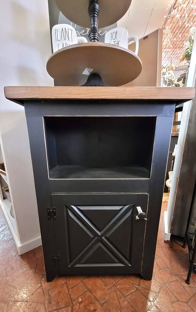 This handsome black cabinet with X-pattern door combines farmhouse charm with practical storage &ndash; perfect for today's homes seeking character and function.