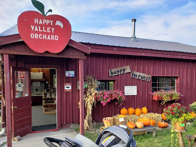 The farm store entrance, framed by seasonal flowers and pumpkins, beckons with promises of cider donuts and other apple-centric delights inside.
