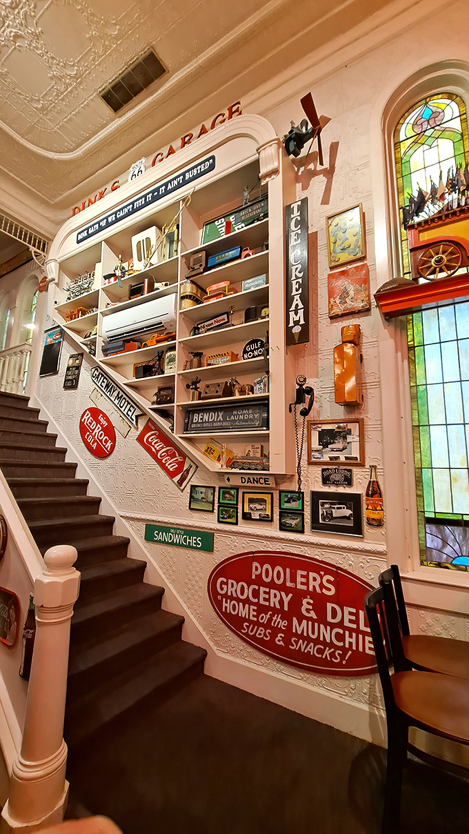 The staircase wall transforms into a gallery of automotive history, with vintage signs guiding you to more treasures upstairs.