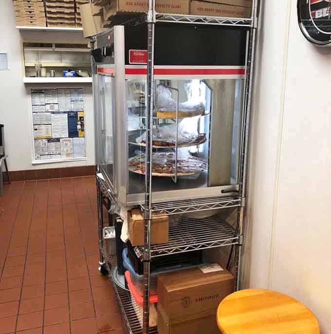 Behind the scenes, pizzas wait their turn in the display rack, ready to deliver happiness to hungry customers throughout the day.