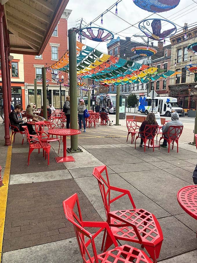 Bright red outdoor seating under colorful art installations creates the perfect spot to enjoy your fresh-baked purchases immediately.