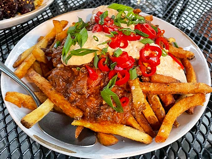A mountain of crispy fries smothered in hearty chili and topped with cooling cream. Fork and knife required, napkins essential.