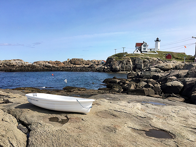 A peaceful cove provides the perfect vantage point for lighthouse viewing, complete with a boat ready for its photo op.