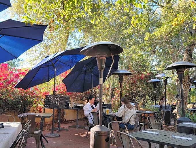 Dining Patio: A shaded oasis where blue umbrellas, mature trees, and the gentle Phoenix breeze create the perfect backdrop for al fresco Italian feasting.