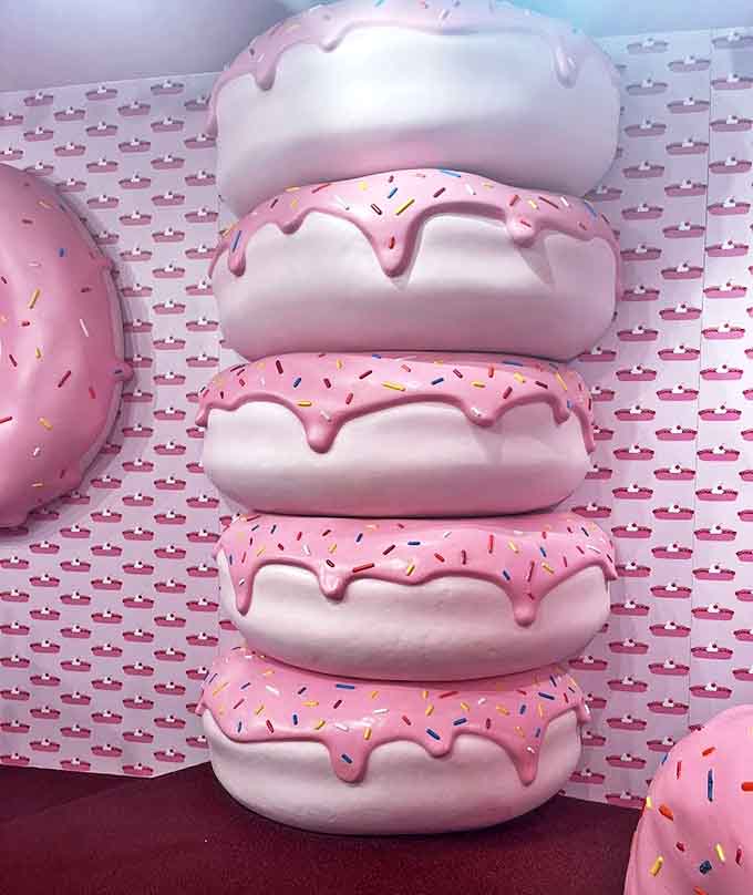 A towering stack of pink-frosted donuts challenges our perception of scale while celebrating dessert's role in popular culture.