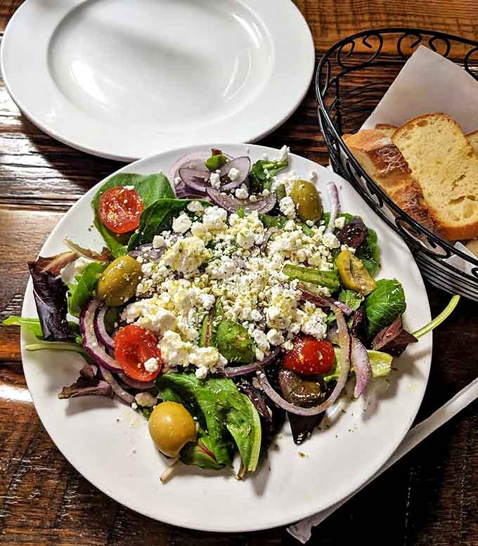 Goat cheese crumbles over fresh greens prove that salads at pizza joints can be legitimate menu stars, not just afterthoughts.