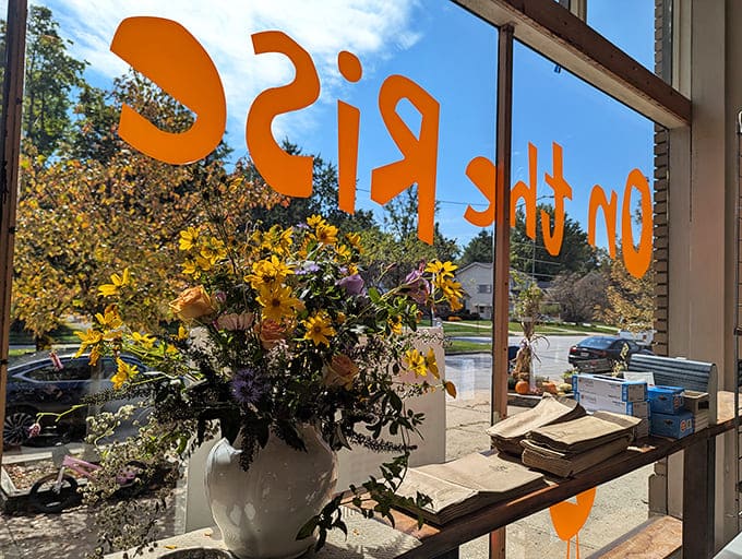 Seasonal flowers in the window remind you that this bakery changes with the seasons, like a delicious calendar you can actually eat.