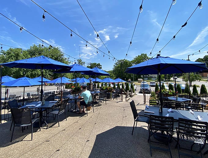 Blue umbrellas and string lights transform an ordinary patio into an enchanted garden for al fresco dining on perfect Michigan days.