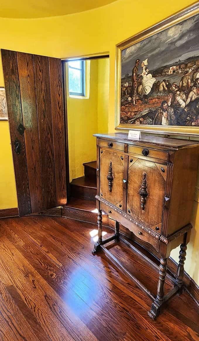 Warm wood tones and yellow walls create a cozy interior atmosphere, this vintage cabinet housing treasures from a bygone literary era.