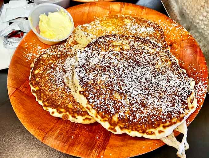 Golden pancakes dusted with powdered sugar await their maple syrup baptism &ndash; breakfast indulgence that proves sometimes the simplest pleasures are the most profound.