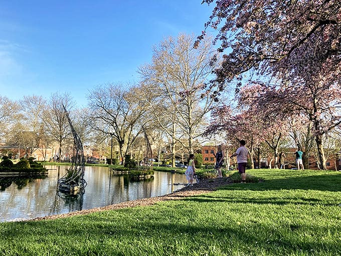 Cherry blossom season brings pink-tinged magic to the park, creating a dreamy backdrop for the sculptural green figures.