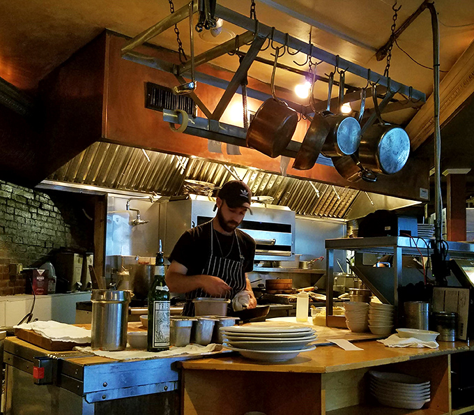 Behind every perfect plate is a skilled kitchen team, working with focused precision while surrounded by hanging pots and professional equipment.