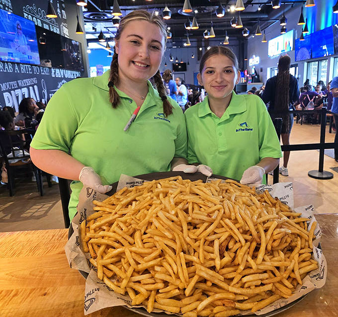 Friendly team members showcase a mountain of golden fries that could feed a small army of hungry gamers.