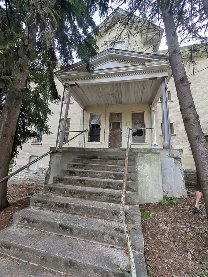 Weathered concrete steps lead to a boarded entrance, one of the buildings still awaiting its turn in the ongoing restoration of this massive complex.