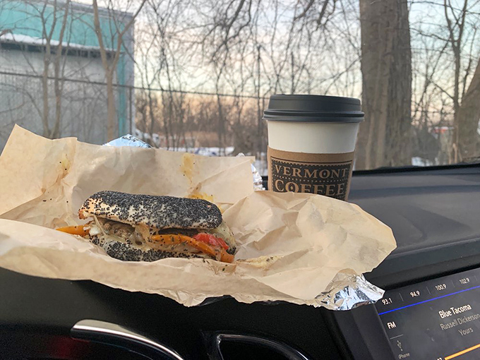 Car dashboard dining at its finest: a poppy seed bagel sandwich and Vermont Coffee Company brew make commuting almost bearable.