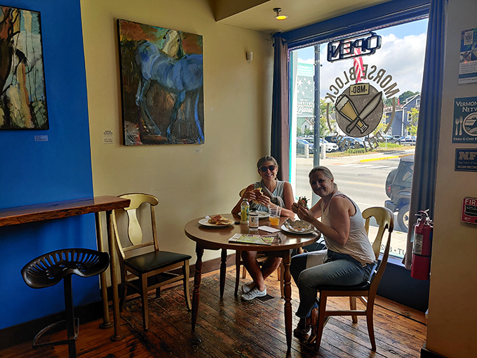 Happy diners share a moment of sandwich bliss by the window &ndash; the universal expression of "you've got to try this" needs no translation.