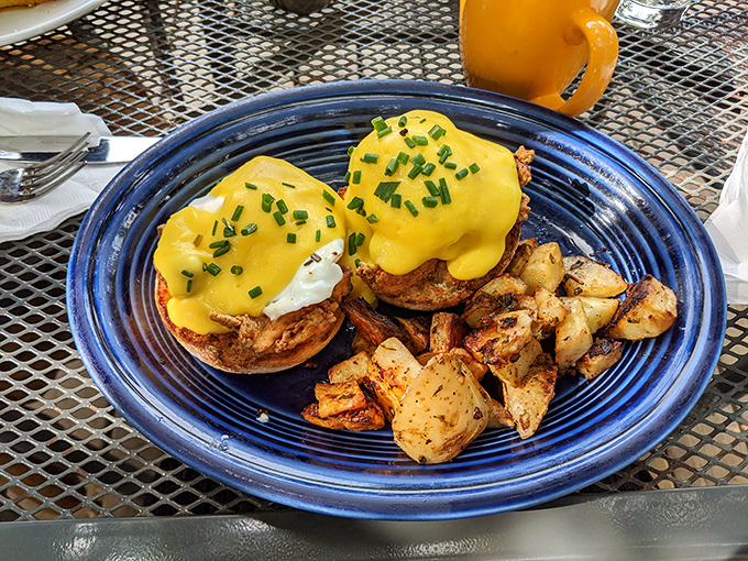 Eggs Benedict perfection &ndash; golden hollandaise cascading over poached eggs atop English muffins with crispy potatoes alongside.