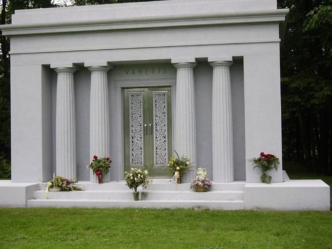 The Vanetti mausoleum stands like a miniature Greek temple, its classical columns framing ornate doors that seem to lead to another world.