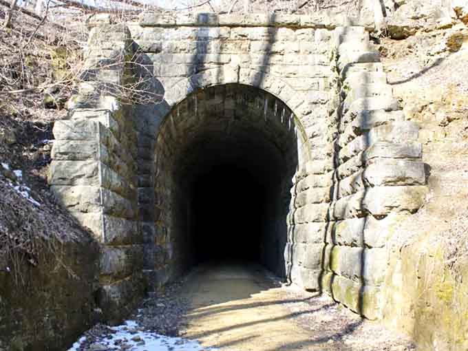 Two young adventurers wave hello from beneath a natural waterfall shower, cooling off in nature's refreshing sprinkler system.