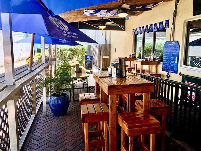 The outdoor seating area transforms Florida sunshine into a proper European biergarten experience, complete with wooden tables and blue umbrellas.