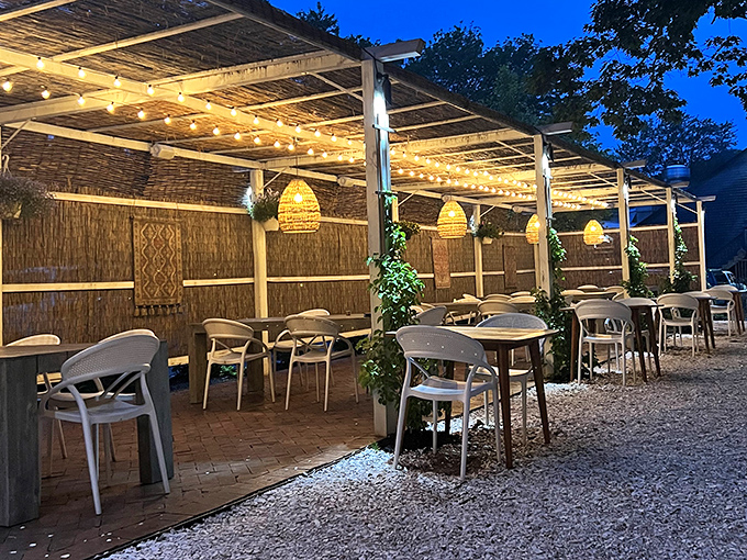 The outdoor dining area transforms into an enchanted garden at dusk, with string lights creating a magical atmosphere for al fresco meals.