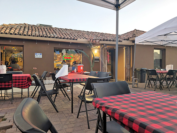 Red checkered tablecloths on the patio create a casual, picnic-like atmosphere for outdoor dining under Arizona skies.