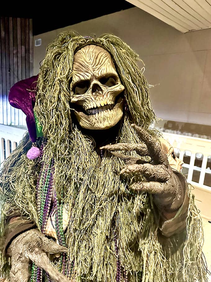A skeletal figure draped in Mardi Gras beads combines festivity with mortality, its grinning face suggesting it knows secrets about the afterlife you'd rather not learn.