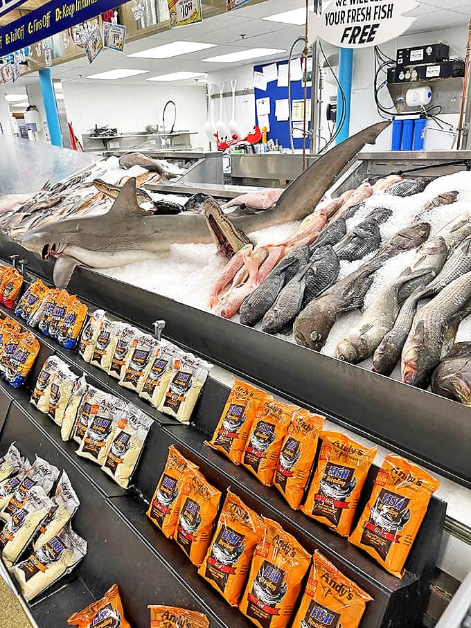 The seafood counter features actual sharks among edible offerings, blurring the line between aquarium visit and dinner preparation.