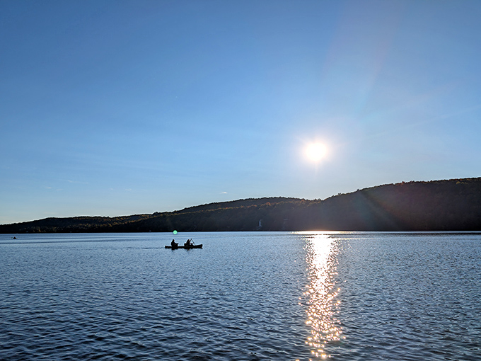 Sunset transforms the lake into liquid gold, creating that magical moment when everyone stops scrolling on their phones to actually look up and appreciate nature's light show.
