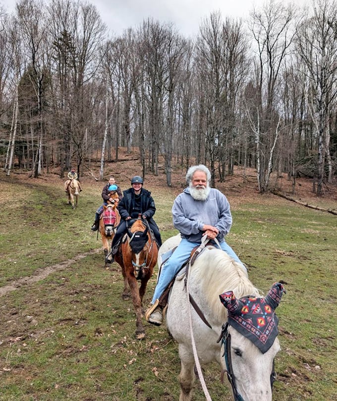 A peaceful procession of horses and riders winds through the forest, experiencing fall foliage at exactly the right pace.