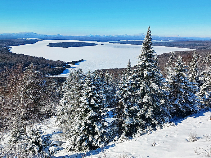 Winter's hush blankets the landscape in pristine white, transforming familiar waters into vast frozen plains beneath snow-capped mountains.