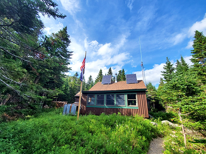 A rustic cabin rests deep in Baxter State Park, with a few solar panels providing the only trace of modern life in the surrounding wilderness.