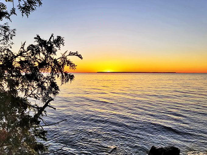 Calm waters reflect a sky ablaze with color. It's like the sun is taking its final bow of the day!