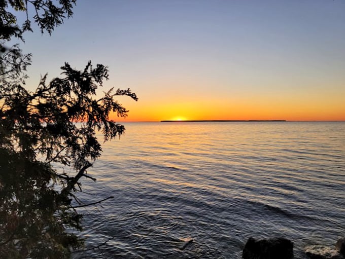 Calm waters reflect a sky ablaze with color. It's like the sun is taking its final bow of the day!