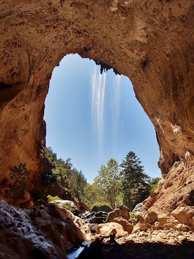 Behold, the world's most impressive natural shower! This cave opening proves that even Mother Nature appreciates good mood lighting.