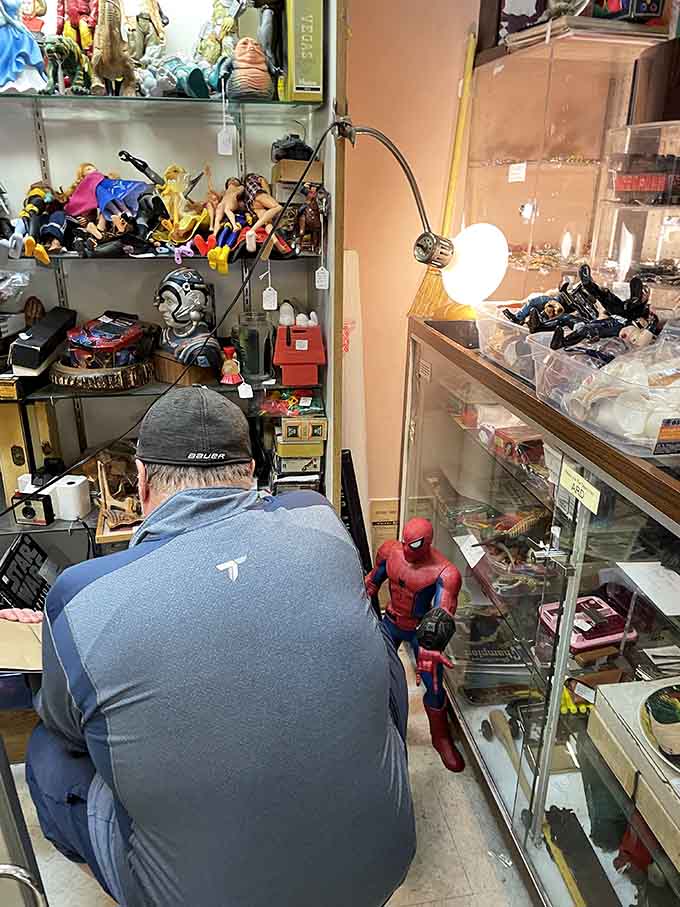 A dedicated treasure hunter examines the merchandise closely, demonstrating the hands-on discovery that makes antique shopping infinitely more satisfying than online browsing.