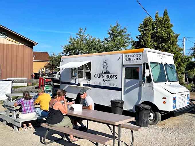 Happy diners gathered around simple picnic tables &ndash; proof that great food creates community, even among strangers just passing through.