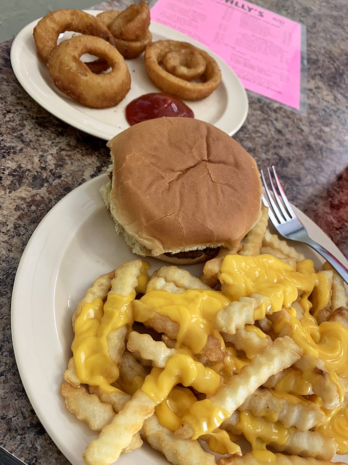 The holy trinity of comfort food: a juicy burger, crispy onion rings, and cheesy fries that'll make your arteries beg for mercy.