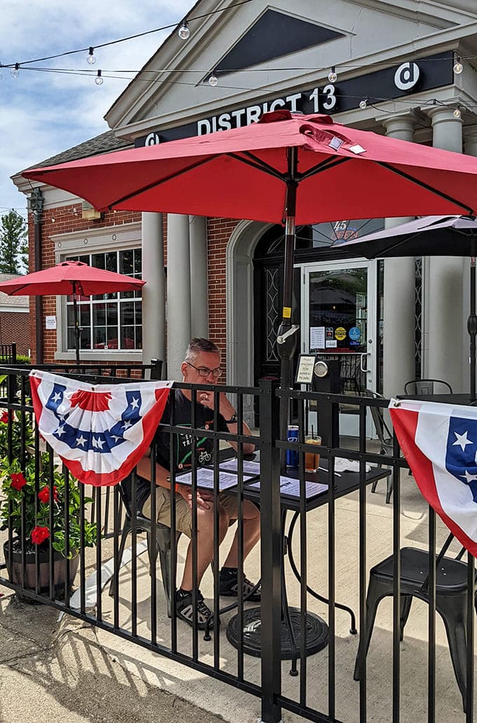 Outdoor seating with red umbrellas offers the perfect spot for people-watching while demolishing that legendary Reuben sandwich.