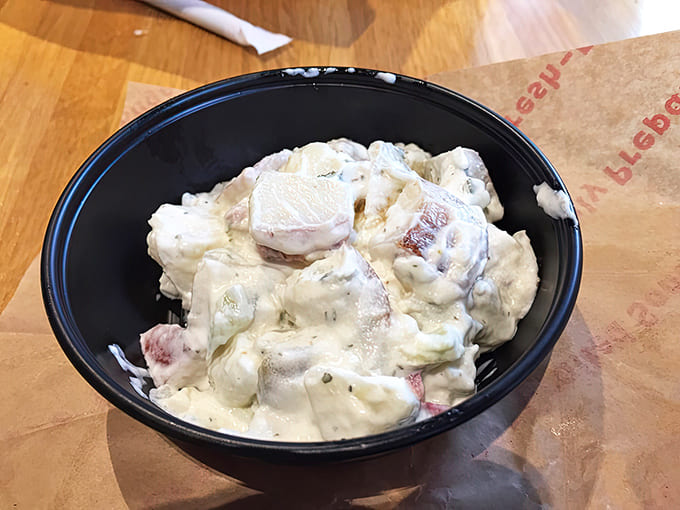 Creamy, herb-flecked potato salad waits patiently in its bowl &ndash; the perfect sidekick to any bagel sandwich lunch combination.