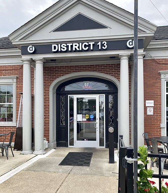 The welcoming entrance with its classical columns and bright flowers creates an inviting approach that promises culinary delights await just beyond the door.