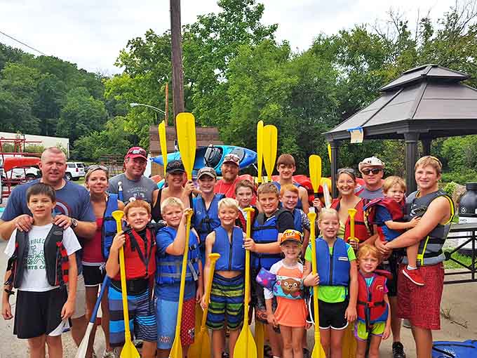 The whole family gathers for a group photo, paddles raised in victory, looking like they just conquered a quest instead of simply floating down a river.