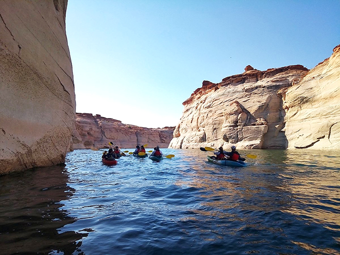 Paddle through liquid gold: kayakers explore the secret passages of Lake Powell's stunning slot canyons.