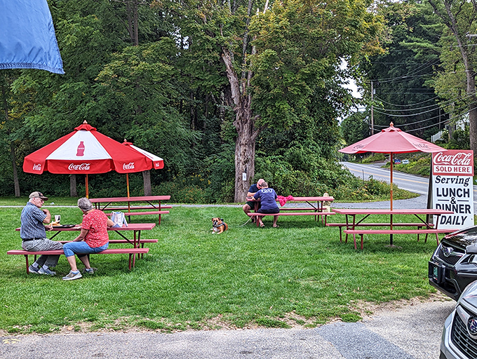 Coca-Cola umbrellas shade picnic tables where strangers become friends over shared appreciation of perfectly crafted comfort food in Vermont's fresh air.