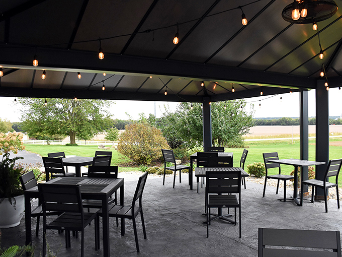 The covered outdoor patio provides al fresco dining with string lights creating a magical atmosphere as evening falls over the countryside.
