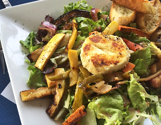 A garden-fresh composition featuring grilled vegetables and what appears to be seared goat cheese, proving seafood isn't the only star here.