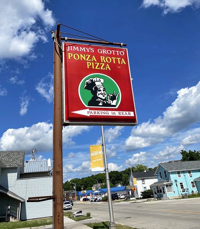 The iconic red sign proudly announces Jimmy's Grotto and its famous Ponza Rotta Pizza, a beacon for hungry travelers seeking Wisconsin's unique treat.