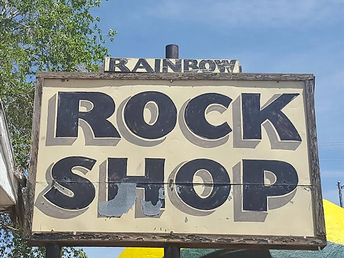 Weathered but iconic, the Rainbow Rock Shop sign promises geological wonders to curious travelers.