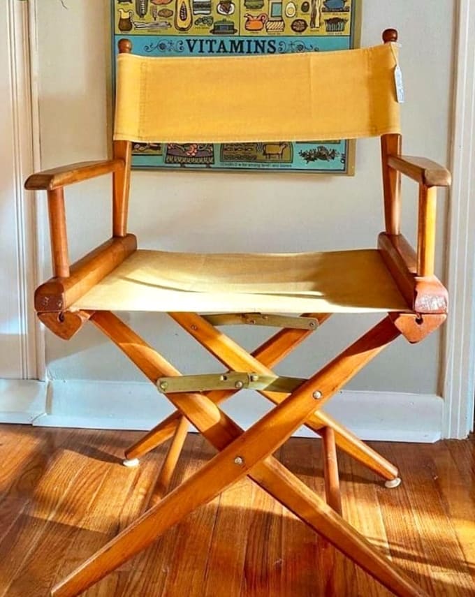 The director's chair sits ready for its close-up, a sunny yellow canvas against warm wood &ndash; perfect for aspiring filmmakers or just making your living room feel Oscar-worthy.